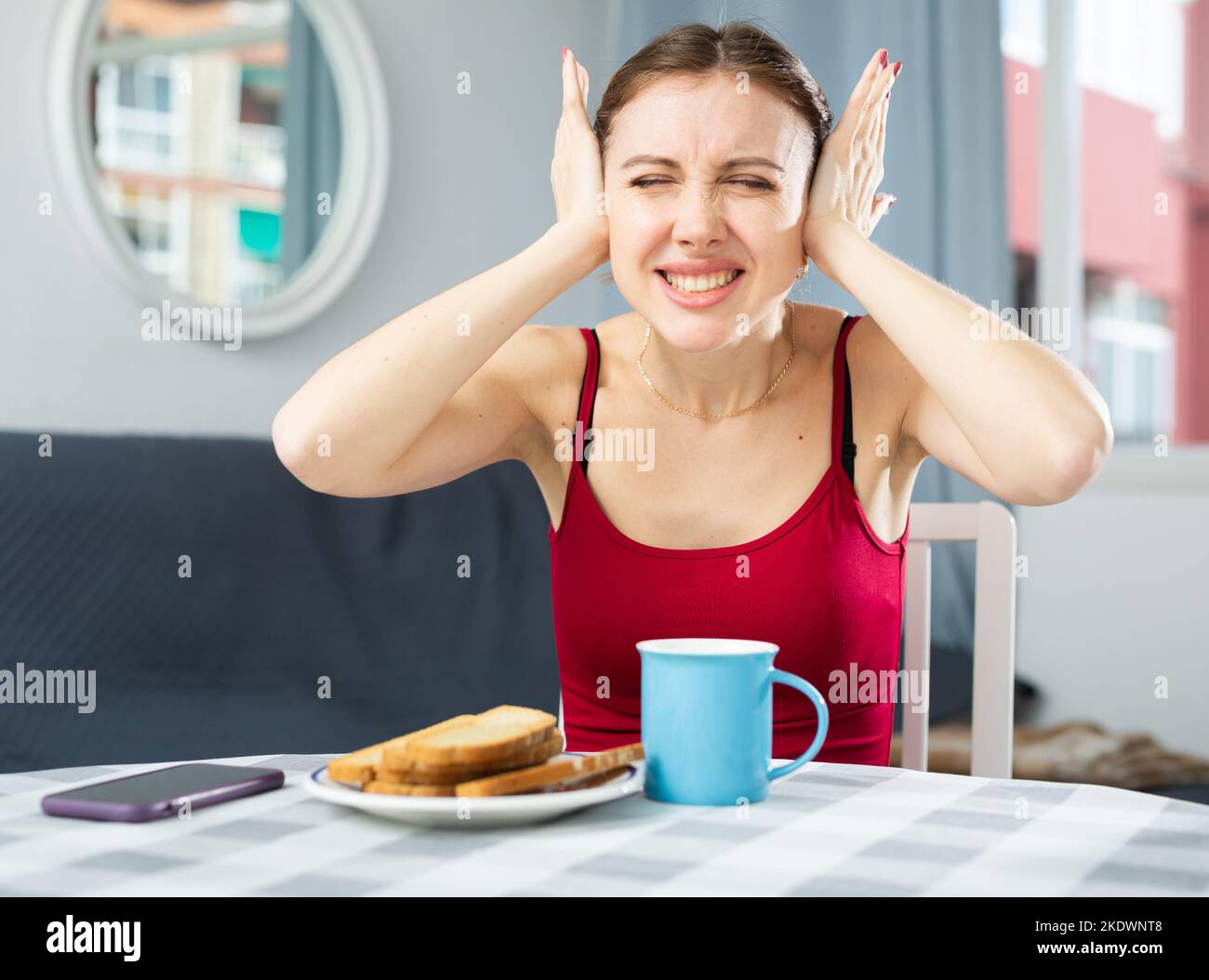 Angry woman covering ears because of loud neighbors Stock Photo - Alamy