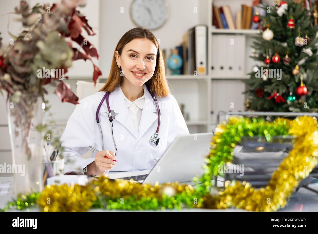 Positive woman doctor working in medical office using laptop during ...