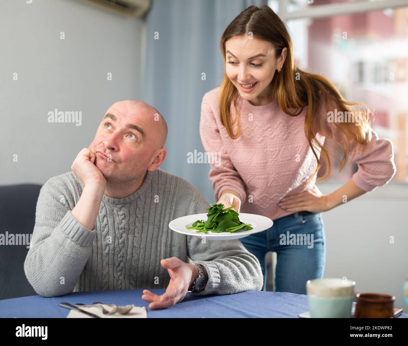 Portrait of a disgruntled man, to whom a young woman brought a plate of ...