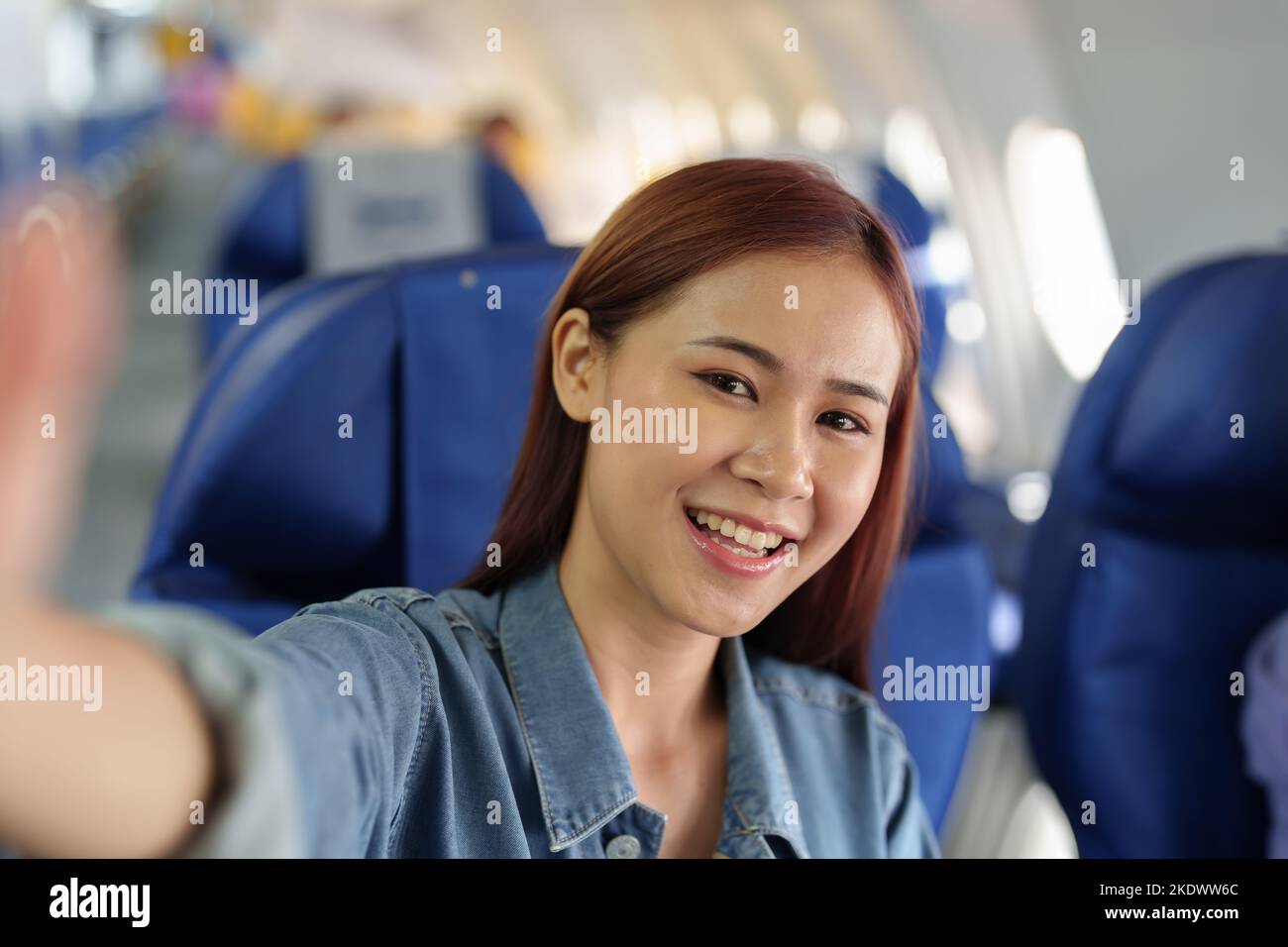 Portrait of an Asian woman taking a selfie or capturing memories while waiting for an economy ...