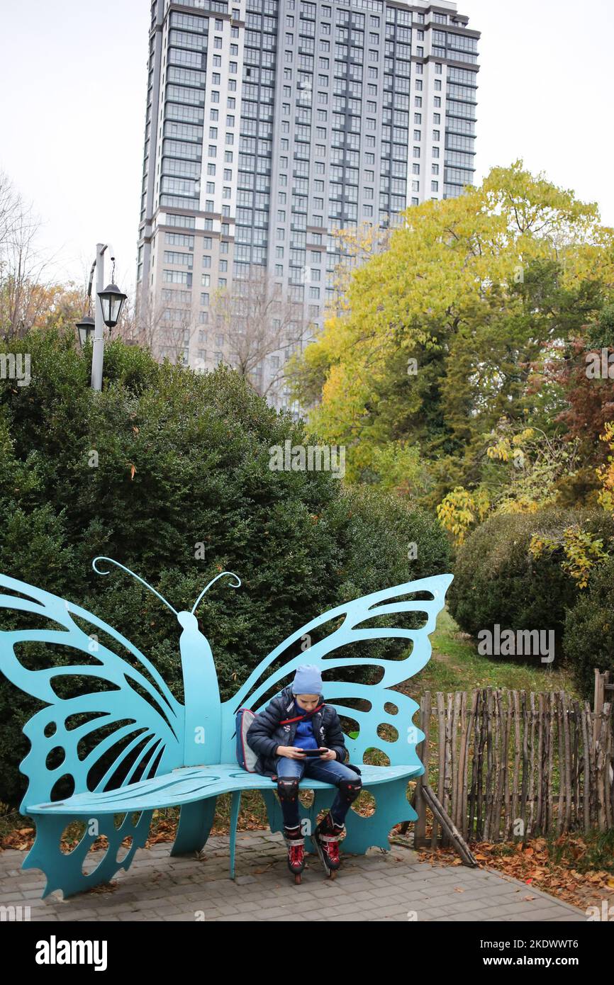A boy is seen sitting on a butterfly-shaped bench against the ...