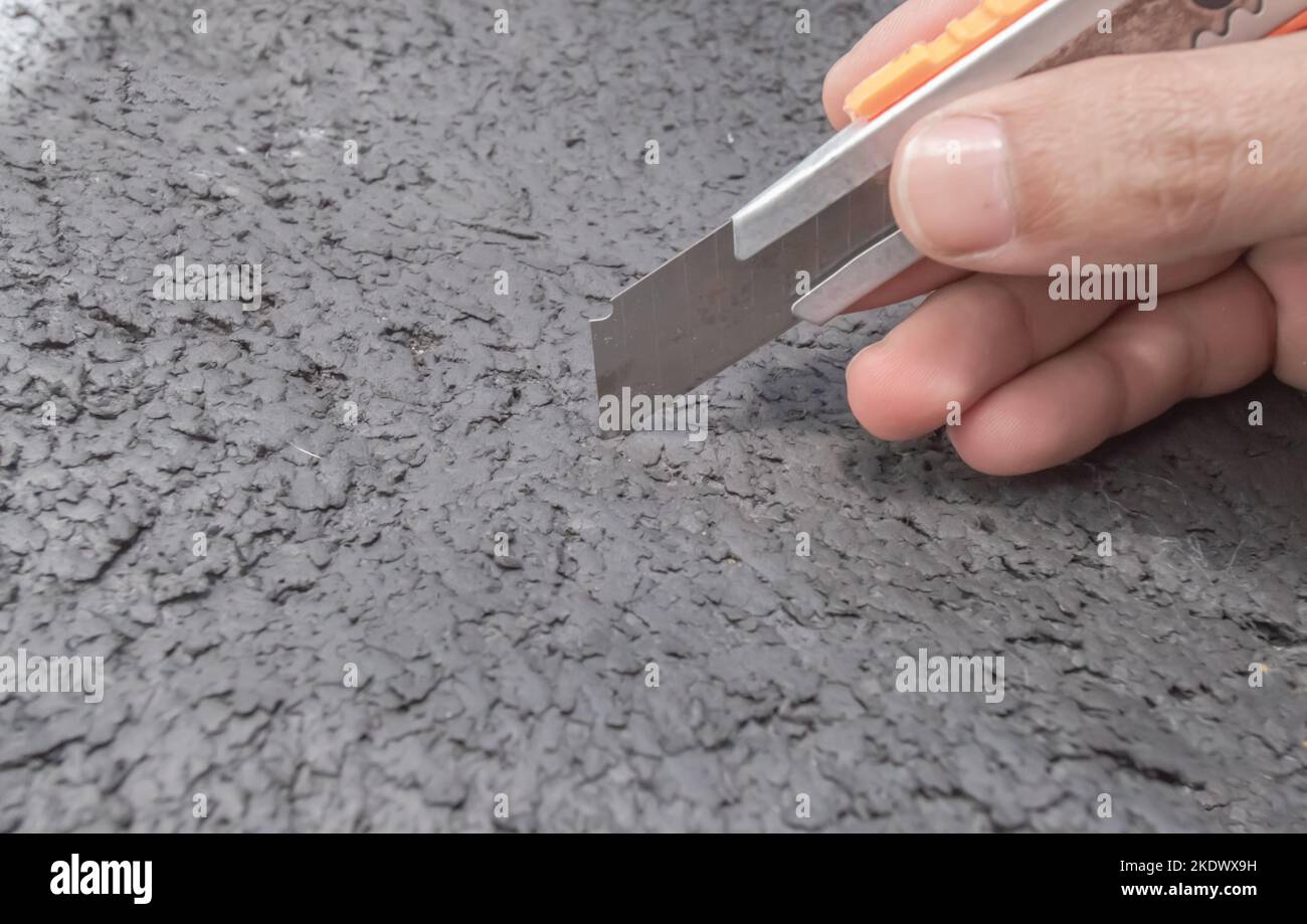 A dry hand holding box cutters and slicing Stock Photo - Alamy