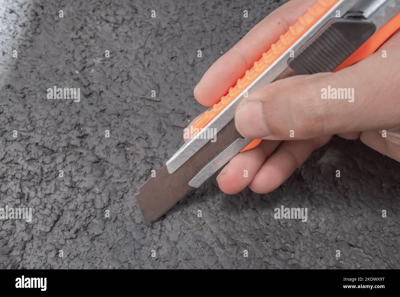 A dry hand holding box cutters and slicing Stock Photo - Alamy