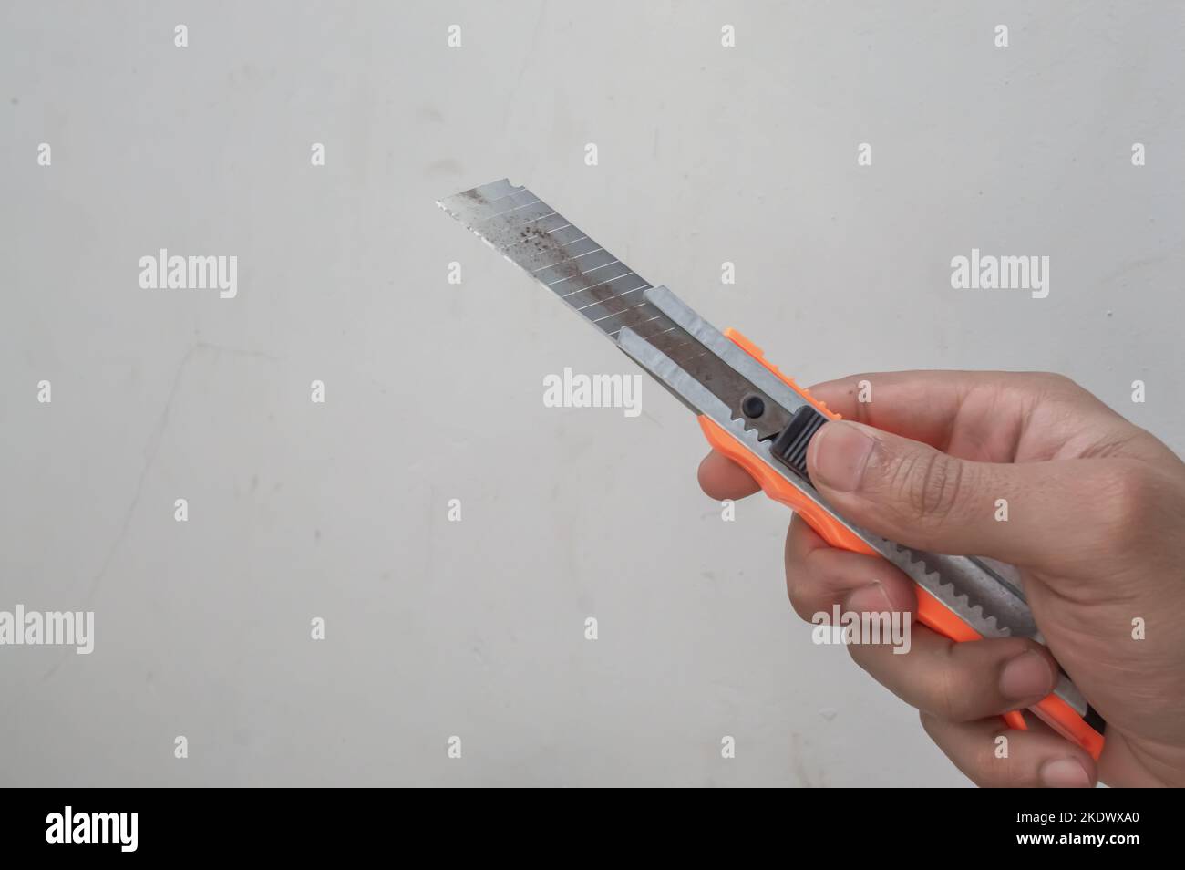 A dry hand holding box cutters and slicing Stock Photo - Alamy