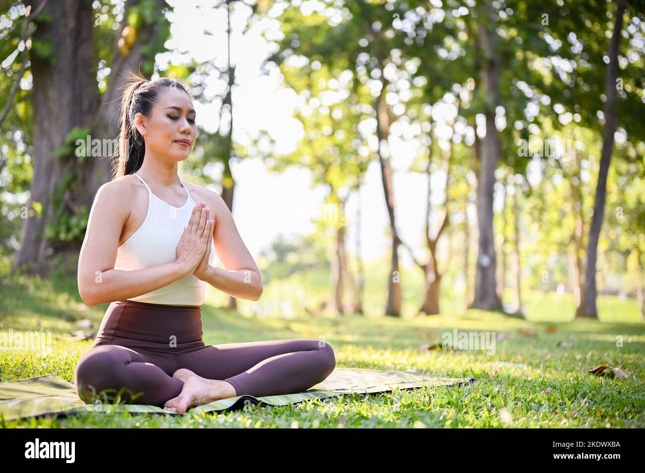 Attractive and charming Asian woman in sportswear sitting on her yoga ...