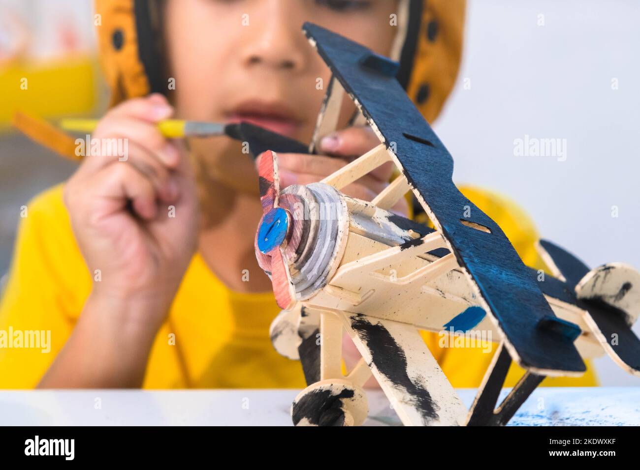 Portrait of a happy Asian girl with a brush painting on a wooden toy ...