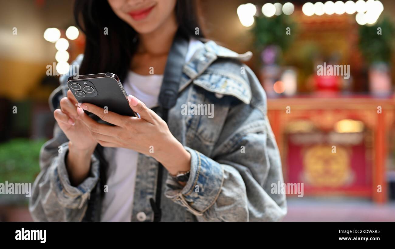 Close up view of young Asian woman holding smartphone during her ... Close up view of young Asian woman holding smartphone during her ...