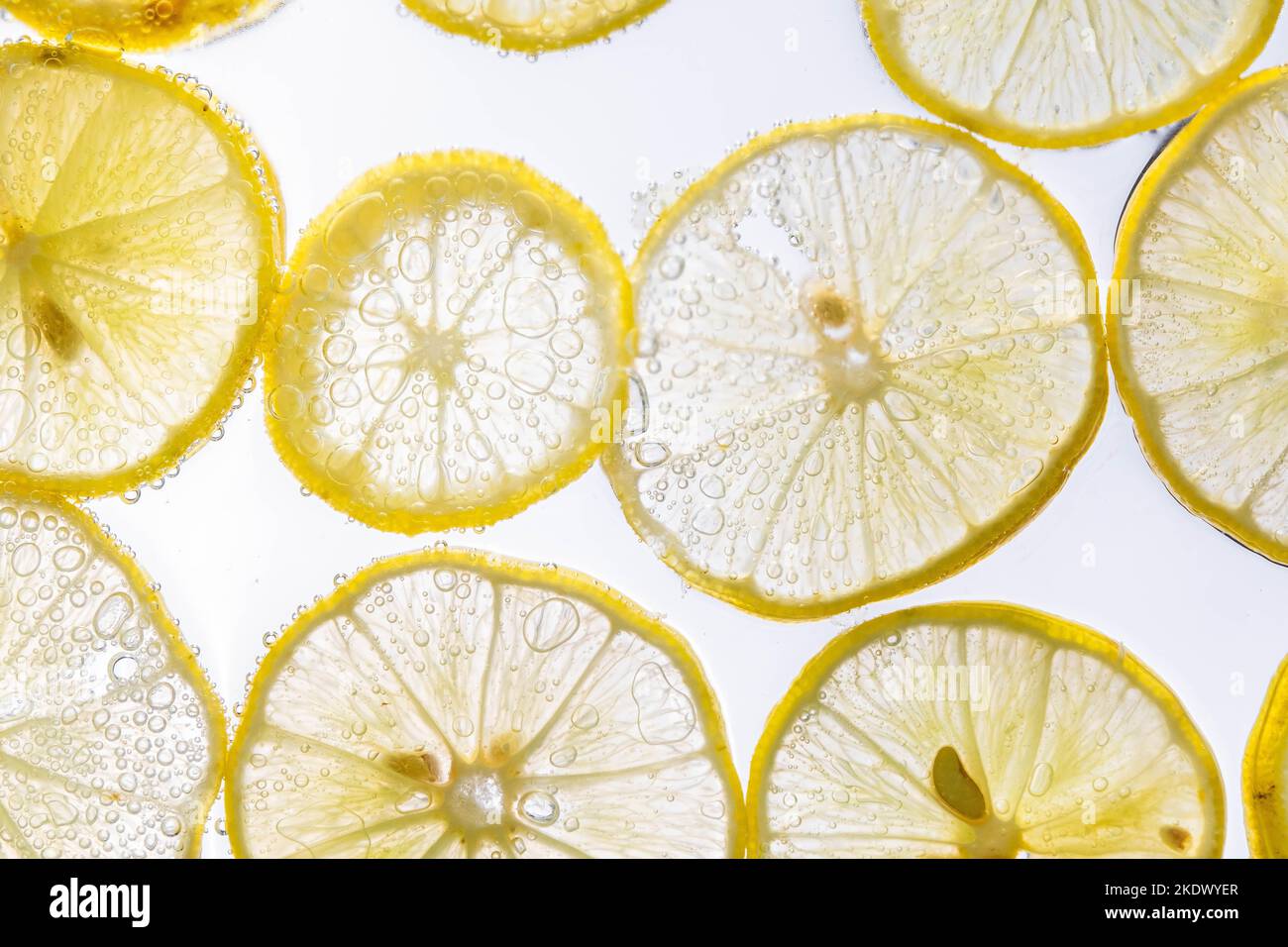Juicy lemon slices with bubbles under water isolated on white background. Yellow lemon slices ...