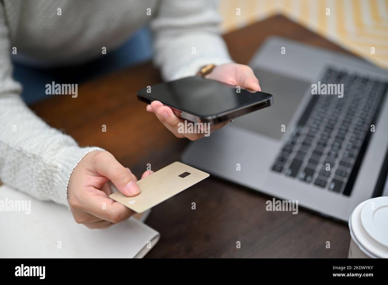 Top view, A female holding a credit card and smartphone over her office ...