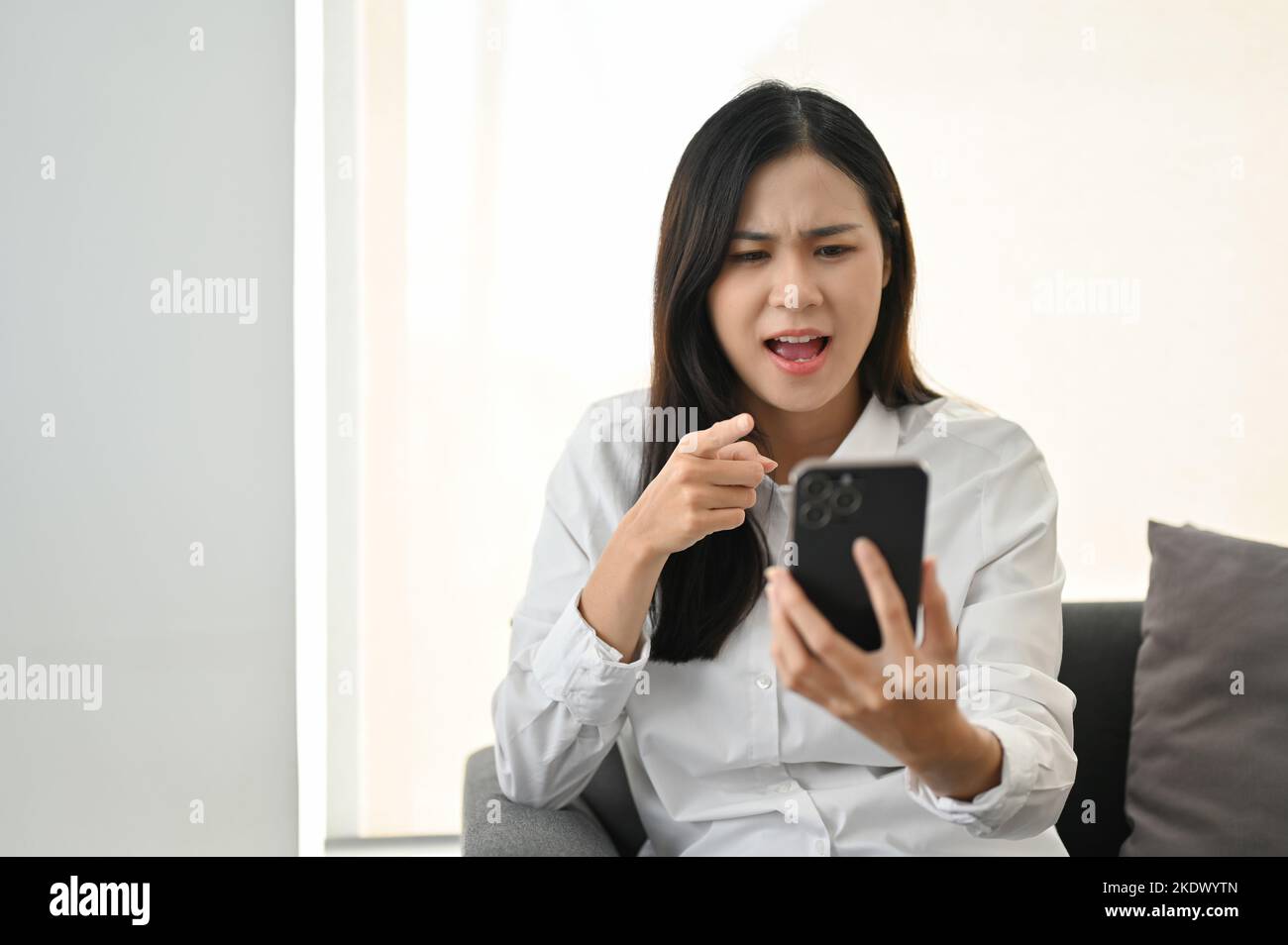 Unhappy and dissatisfied young Asian woman in casual clothes sitting on ...