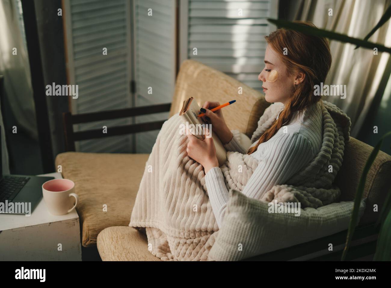 Cute lady with eyes patches at home writing notes on a diary while ...