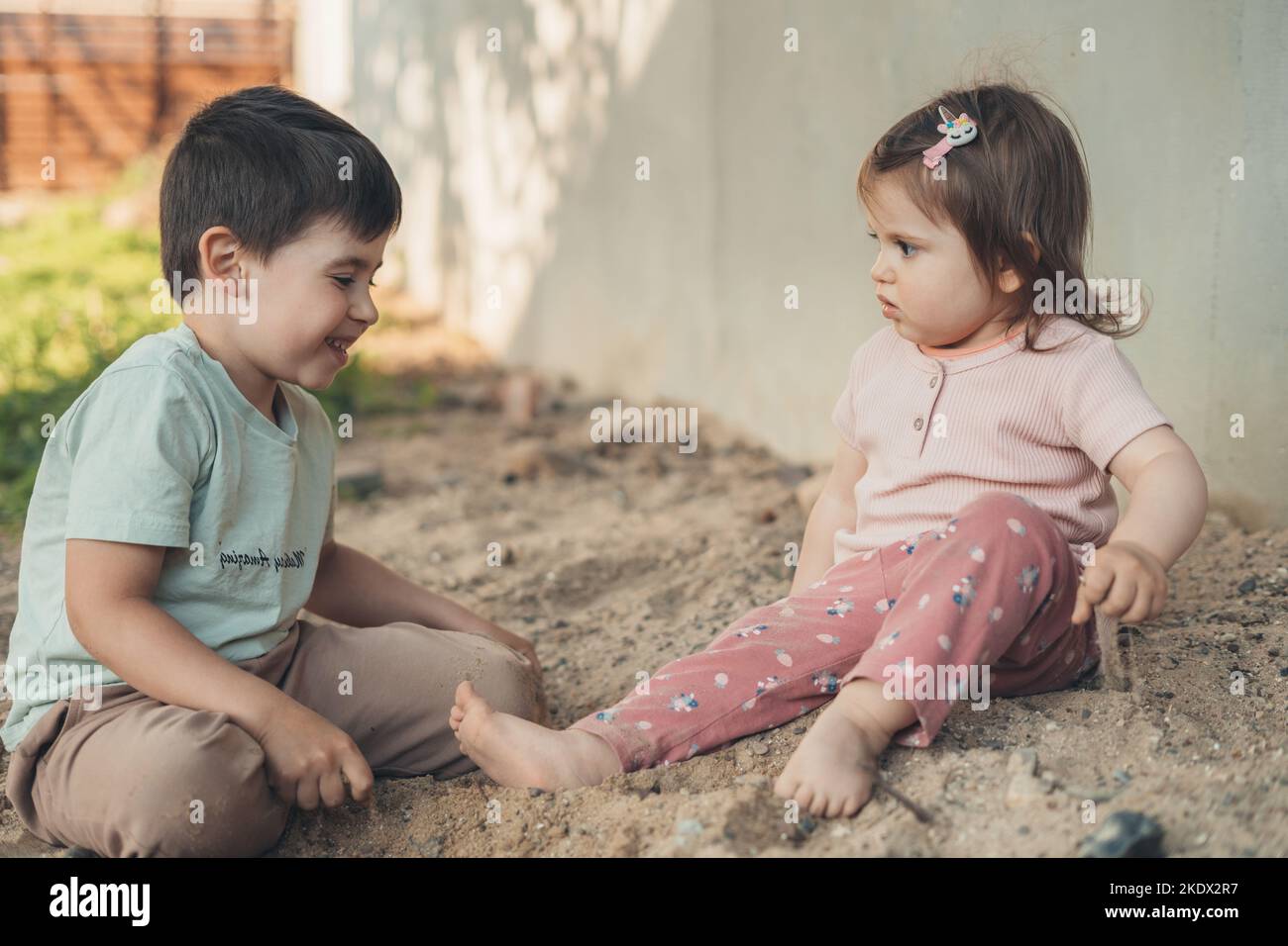 Boy and girl playing together, exploring nature, both sitting on the ...
