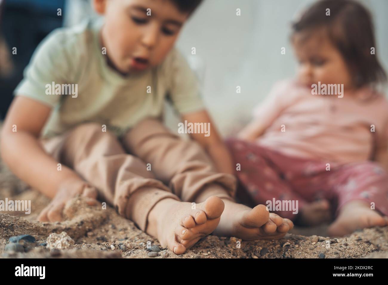 Two little kids playing on sandy playground outdoors together, having ...