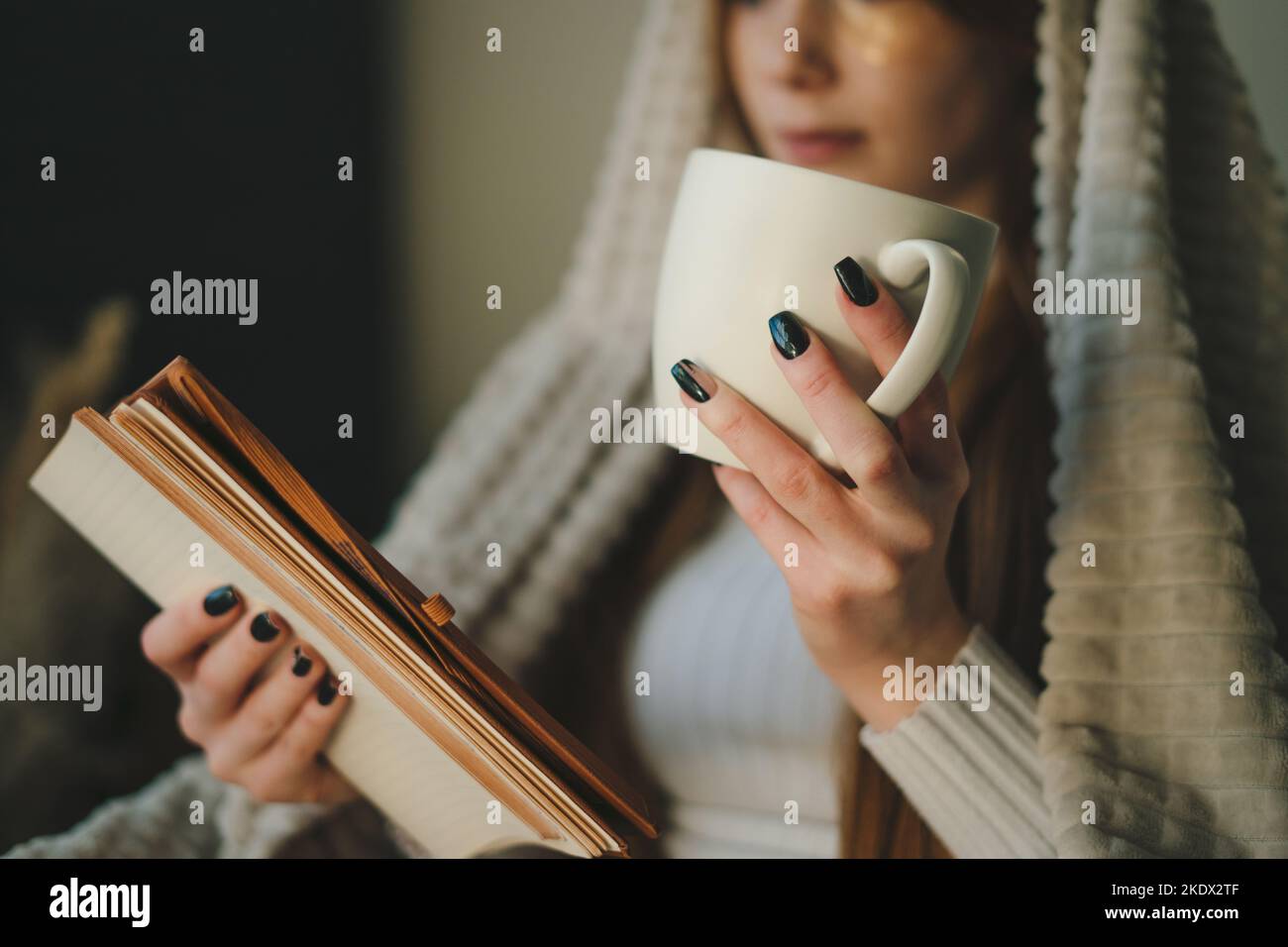 Woman sitting alone on sofa drinking a cup of coffee working or ...