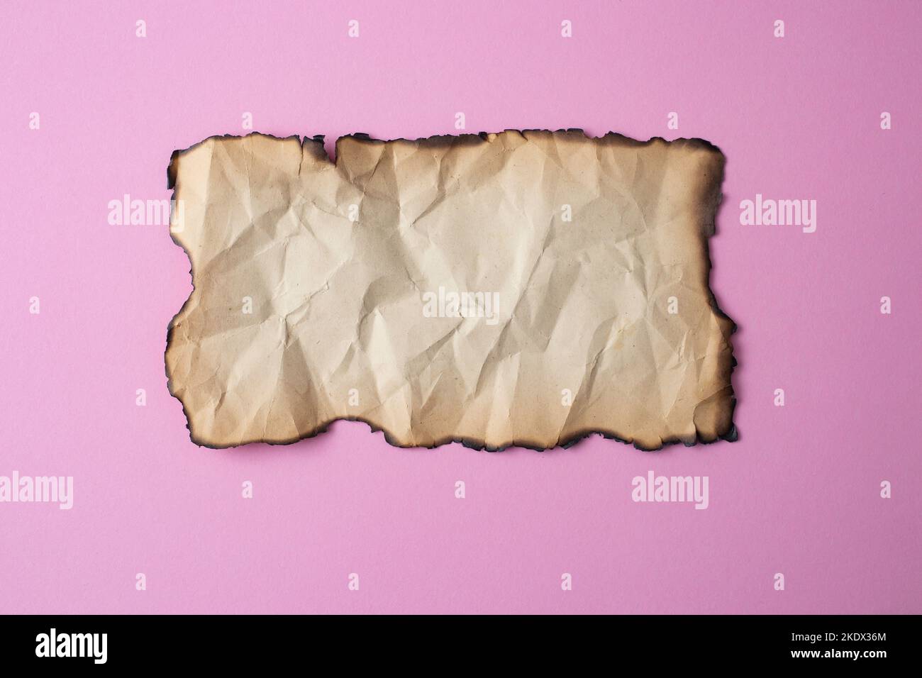 Vintage crumpled paper with burned edges, close up isolated on pink ...