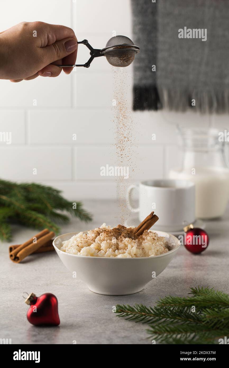 Sprinkle cinnamon over Scandinavian rice porridge in a bowl surrounded ...