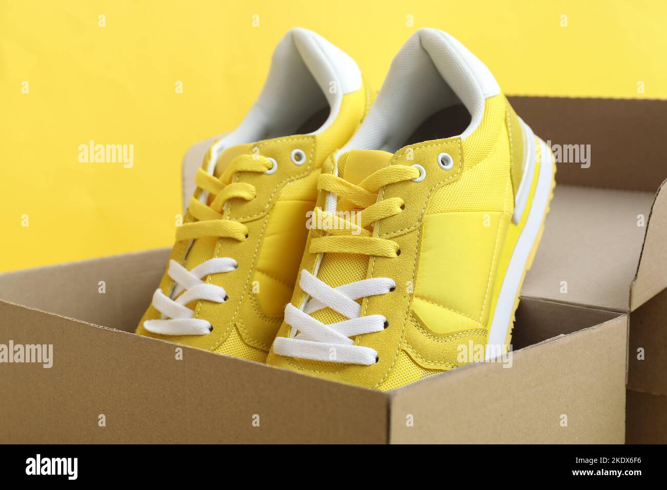 Cardboard box with sneakers on yellow background, closeup Stock Photo ...