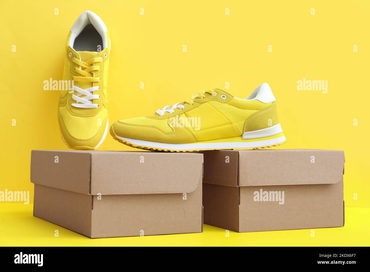Cardboard boxes with sneakers on yellow background Stock Photo - Alamy