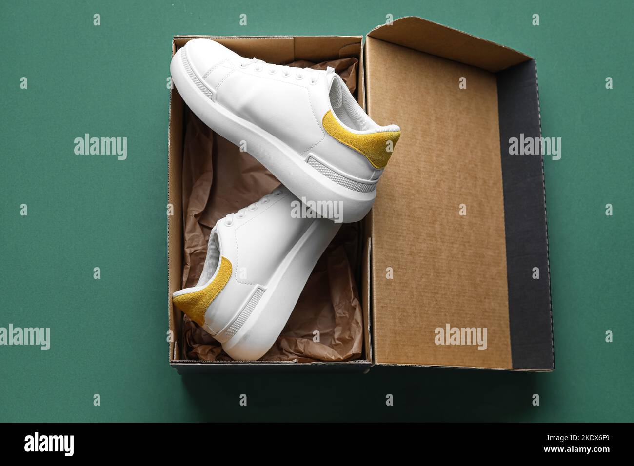 Cardboard box with white sneakers on green background Stock Photo - Alamy