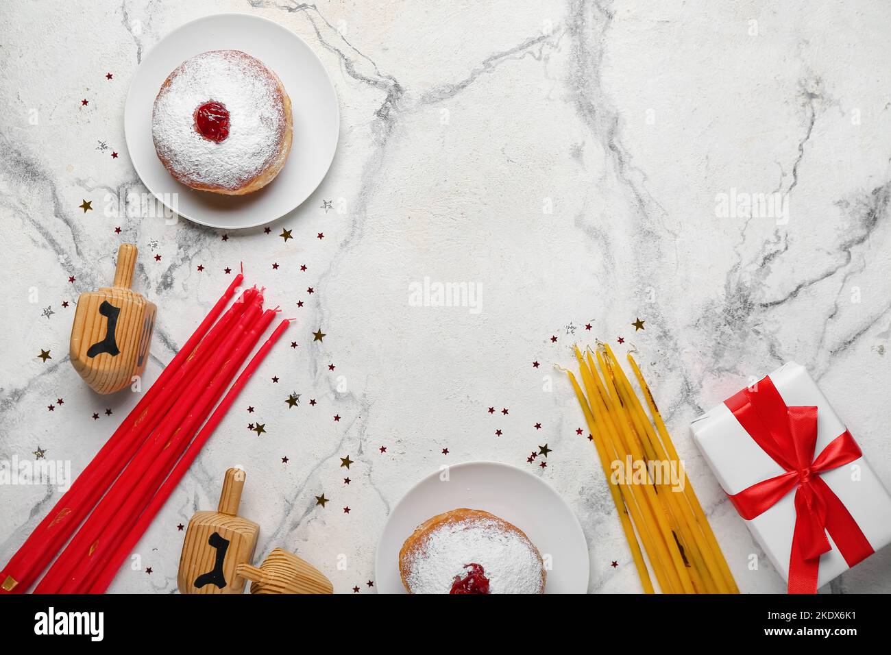 Plates with tasty donuts with dreidels, candles and gift for Hannukah ...