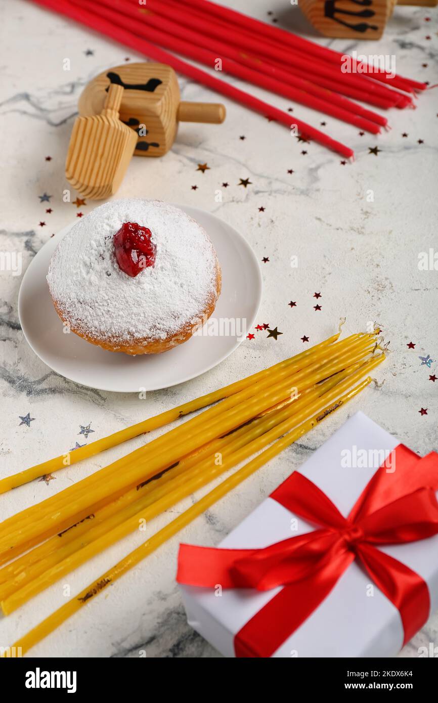 Plate with tasty doughnut with dreidels, candles and gift for Hannukah ...