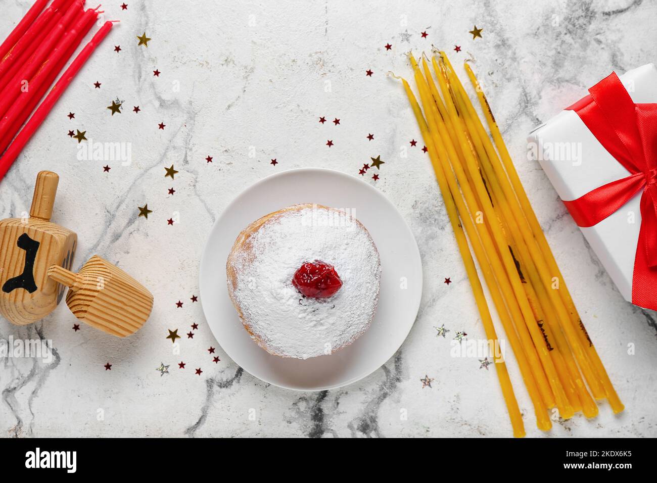 Plate with tasty doughnut with dreidels, candles and gift for Hannukah ...