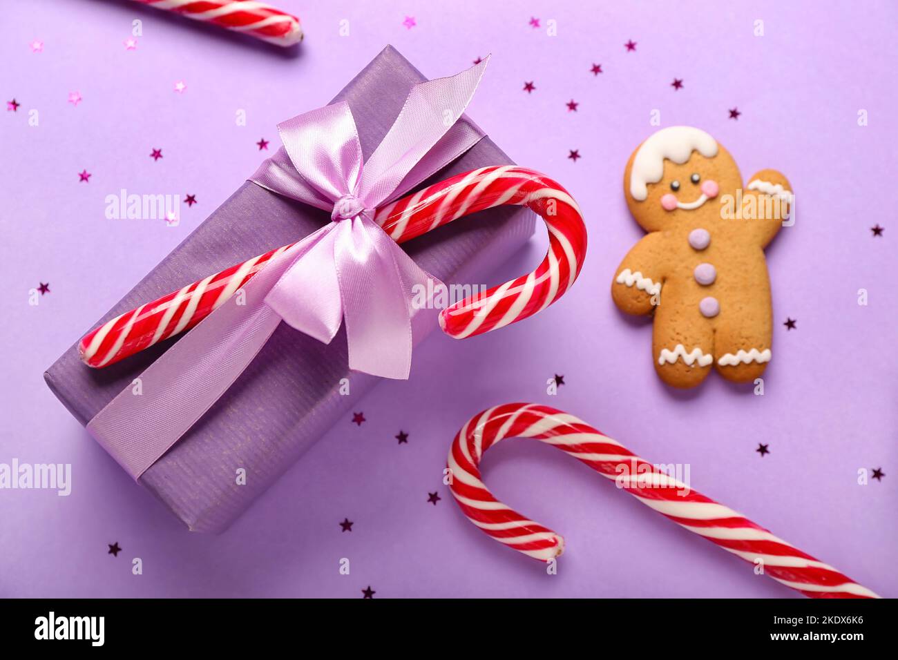 Candy canes with Christmas gift and cookie on lilac background Stock ...