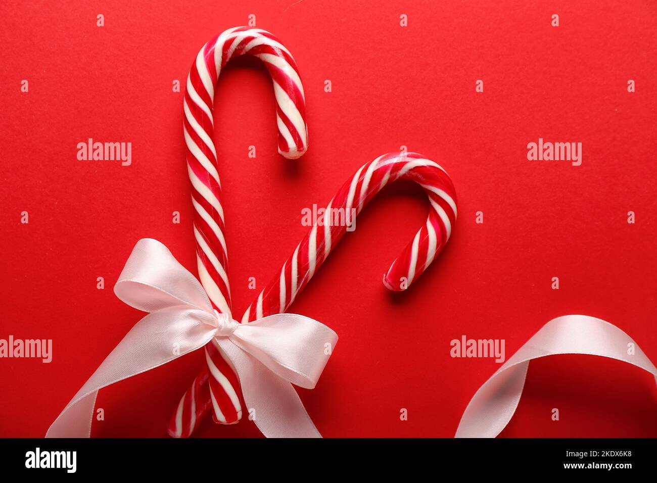Candy canes with bow on red background Stock Photo - Alamy