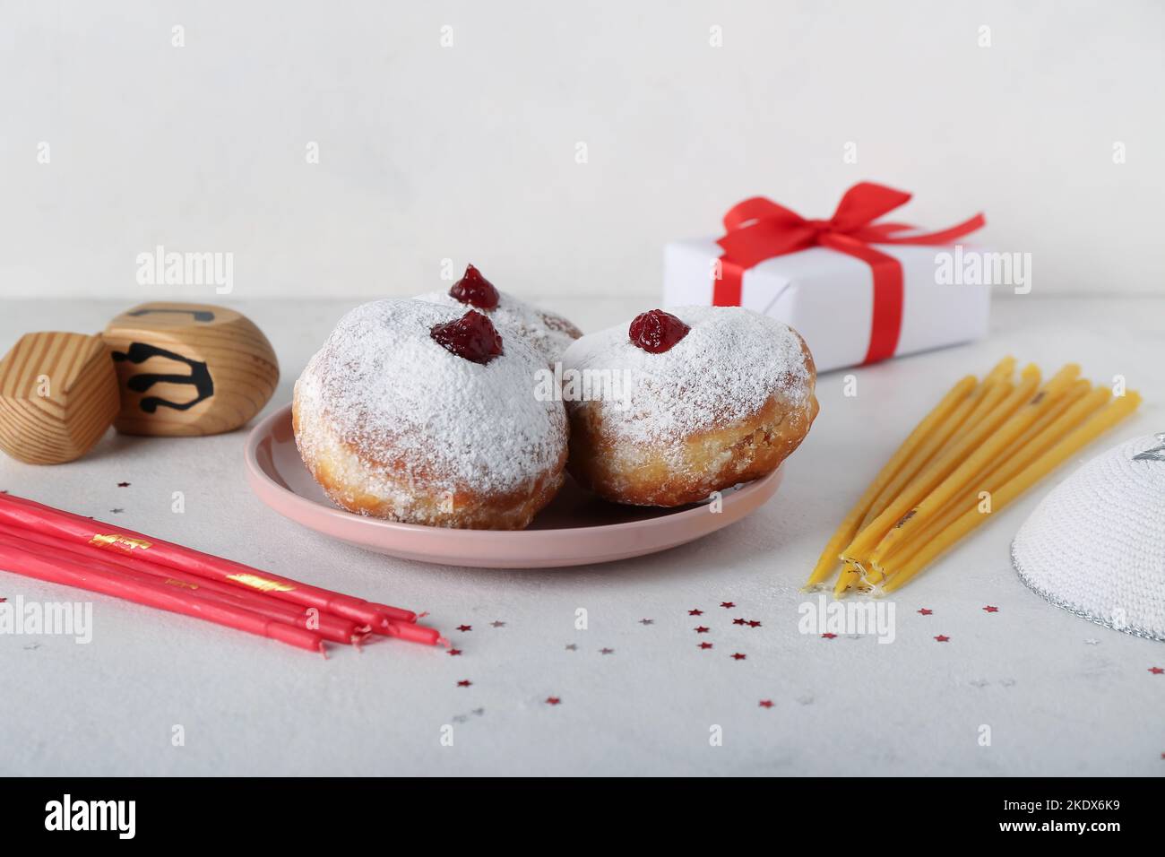 Plate with tasty donuts, dreidels, candles and gift for Hannukah ...