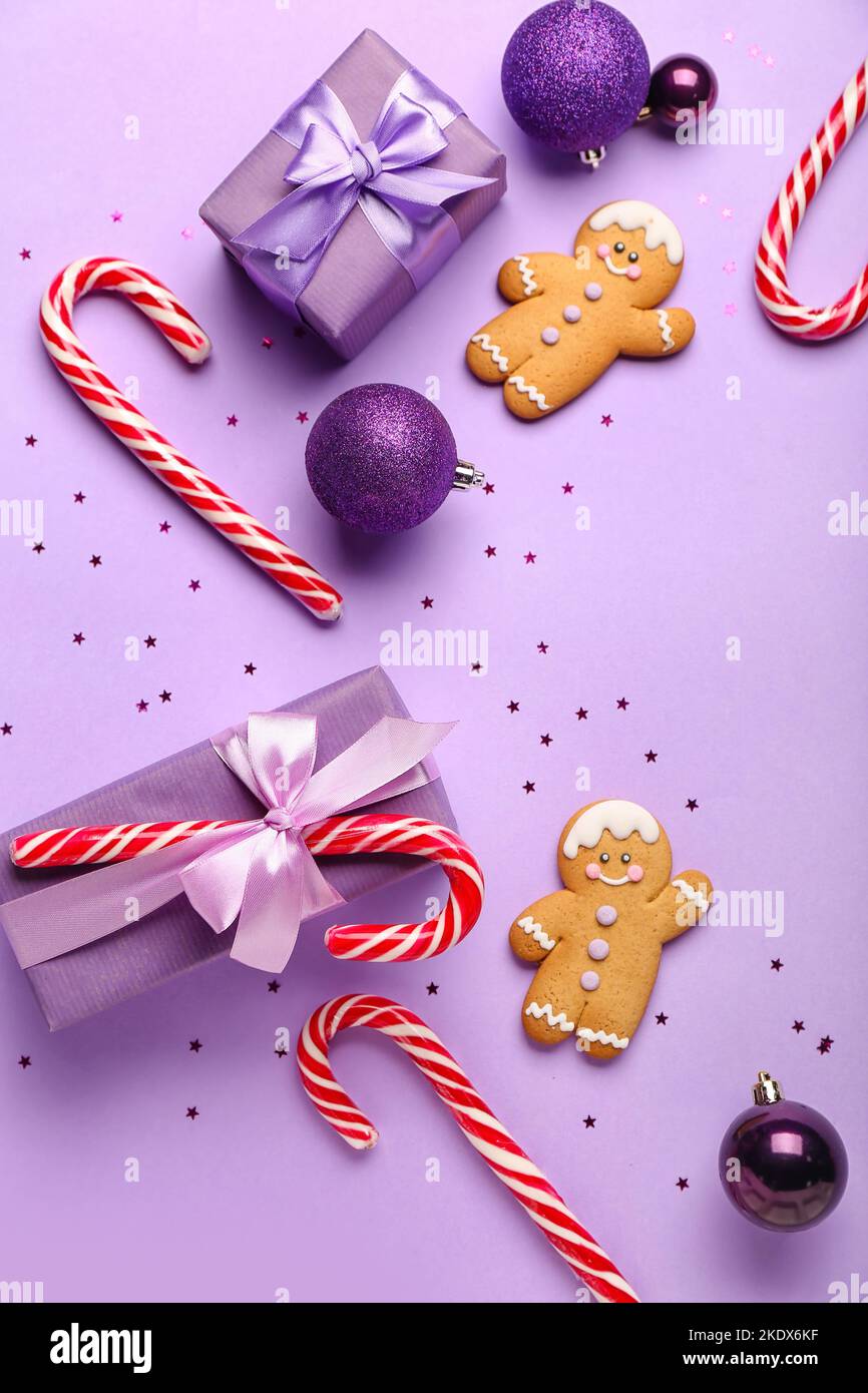 Candy canes with Christmas balls, presents and cookies on lilac ...