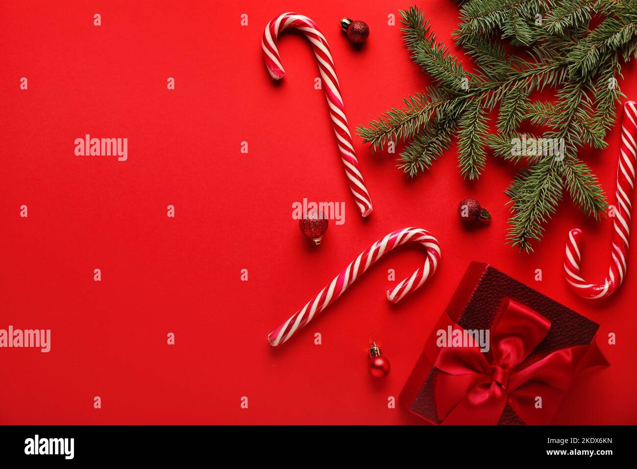 Candy canes with Christmas balls, gift and fir branches on red ...