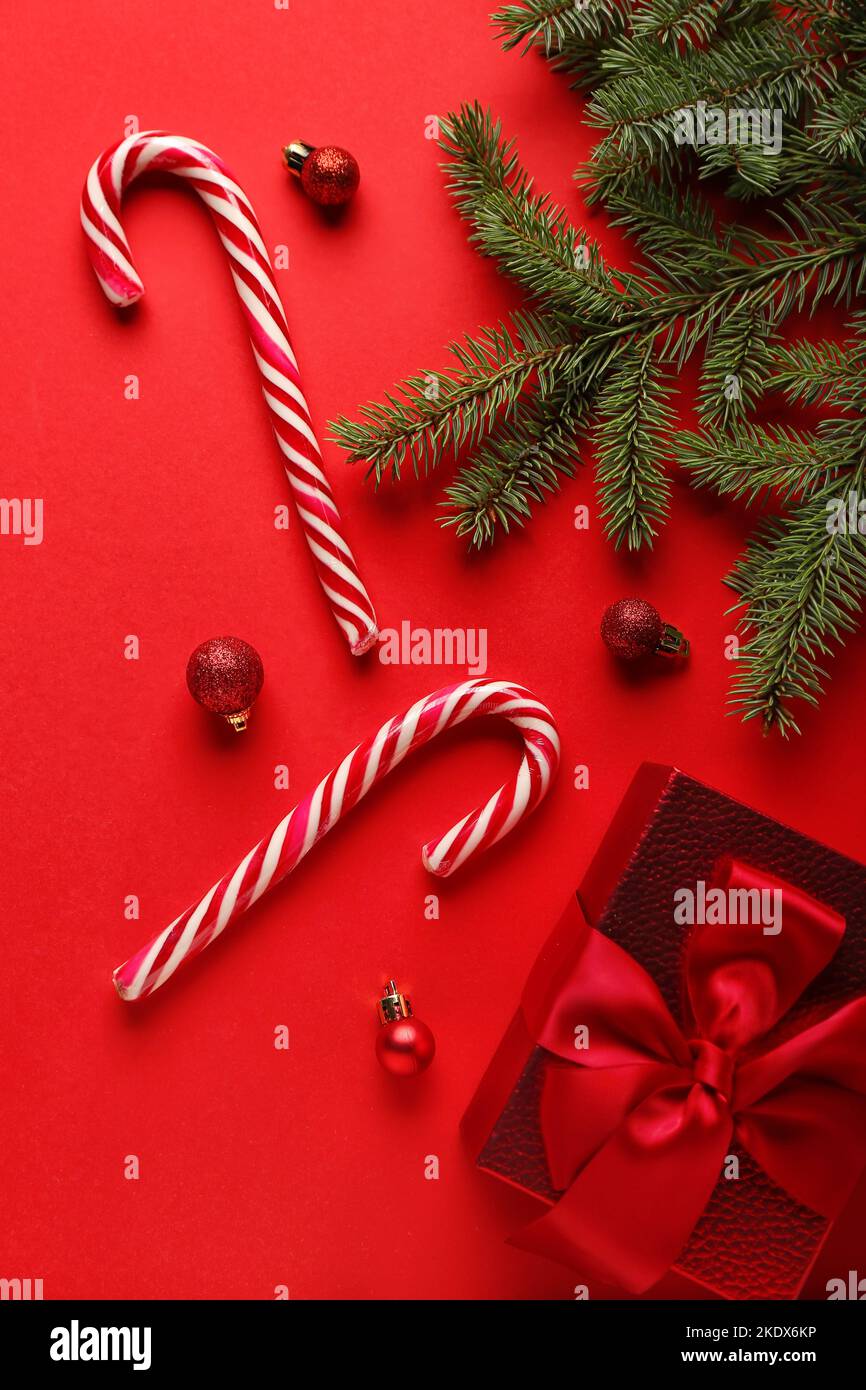 Candy canes with Christmas balls, gift and fir branches on red ...