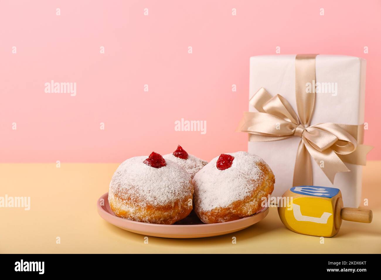 Plate with tasty donuts, dreidel and gift for Hannukah celebration on ...