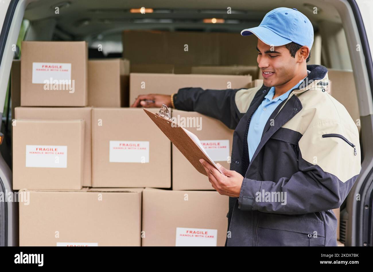 Loading the van for his day of deliveries. a delivery man standing next ...
