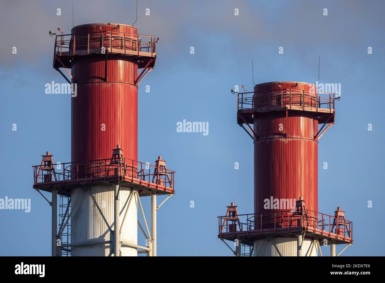 Upper parts of smoking red white metal chimneys under blue sky on a ...