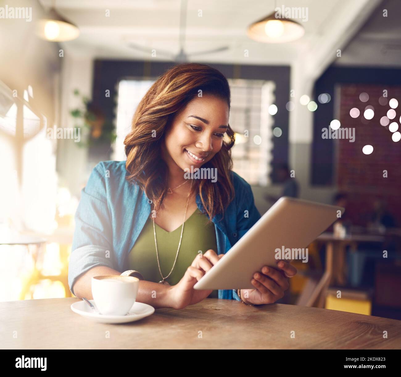 Doing a blog on free wifi. an attractive young woman using a digital ...