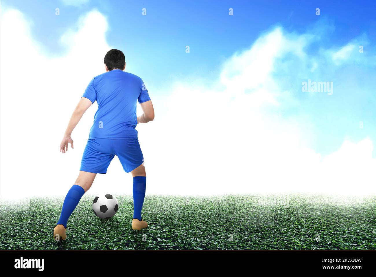 Rear view of Asian football player man in a blue jersey dribbling the ...
