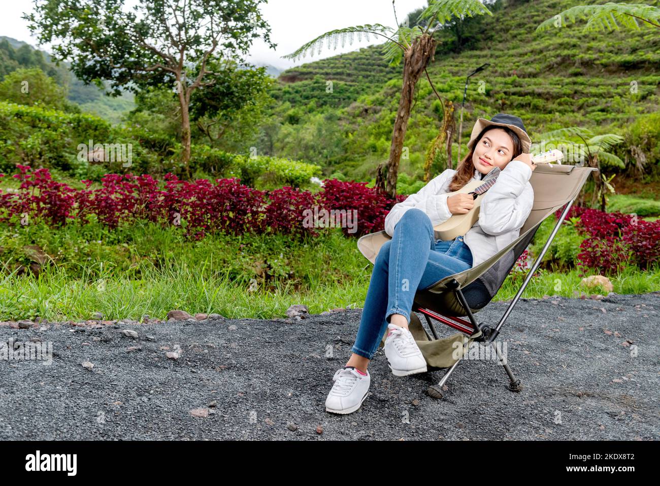 Asian woman playing guitar enjoying camp activity in nature Stock Photo ...