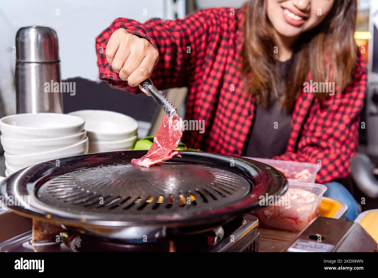Asian woman sitting while grilling barbeque enjoying camp activity in ...