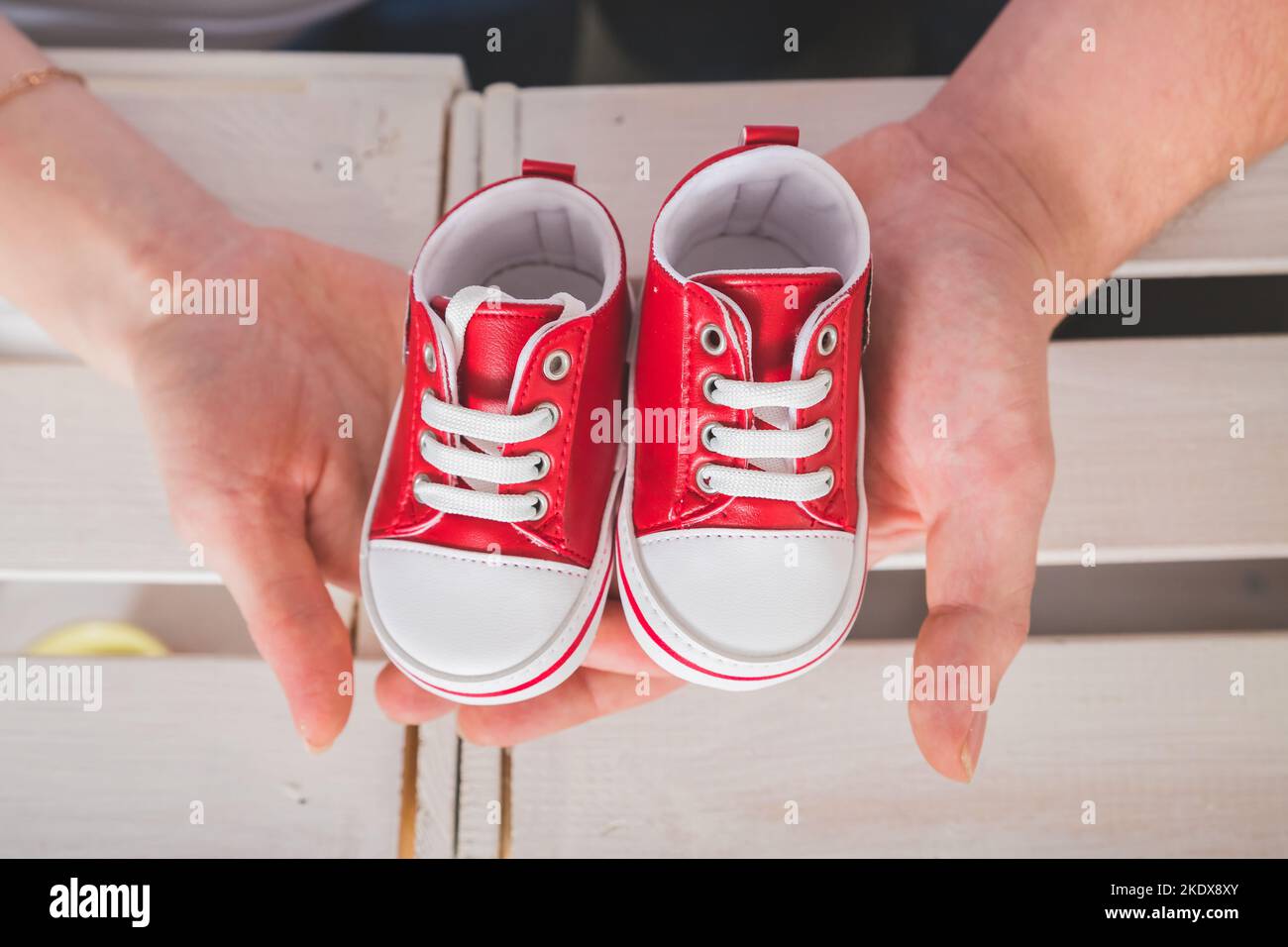 man is holding small red leather shoes in hands. Young white family ...