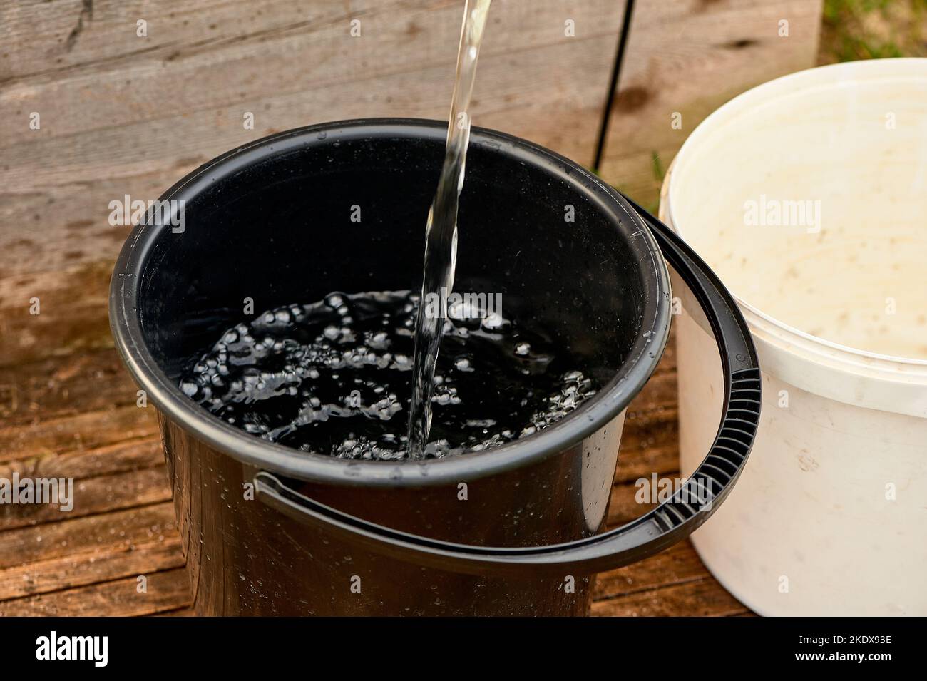 a black plastic bucket is filled with water from the pump Stock Photo ...