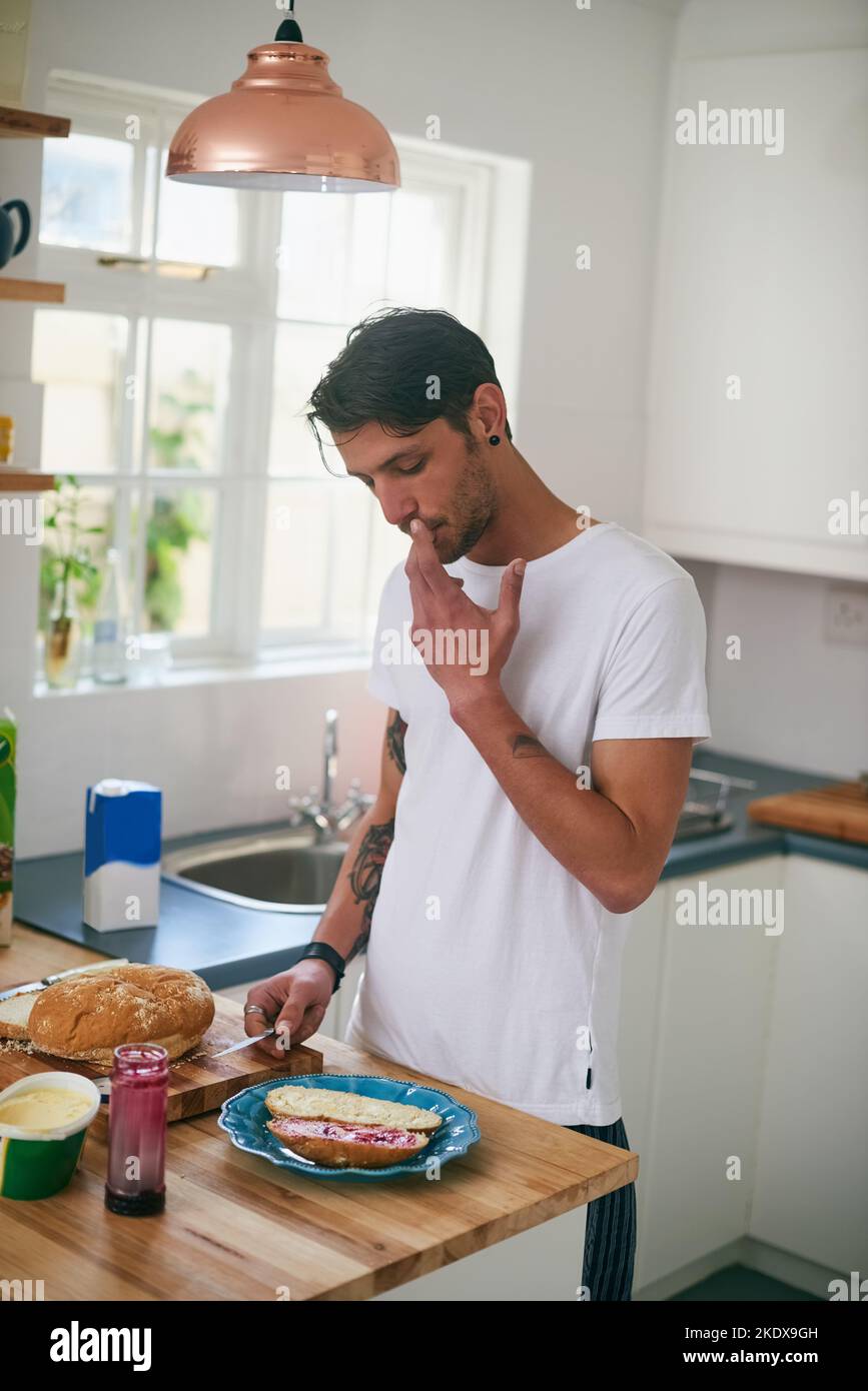 Thats a tasty sandwich. a handsome young man standing in his kitchen ...