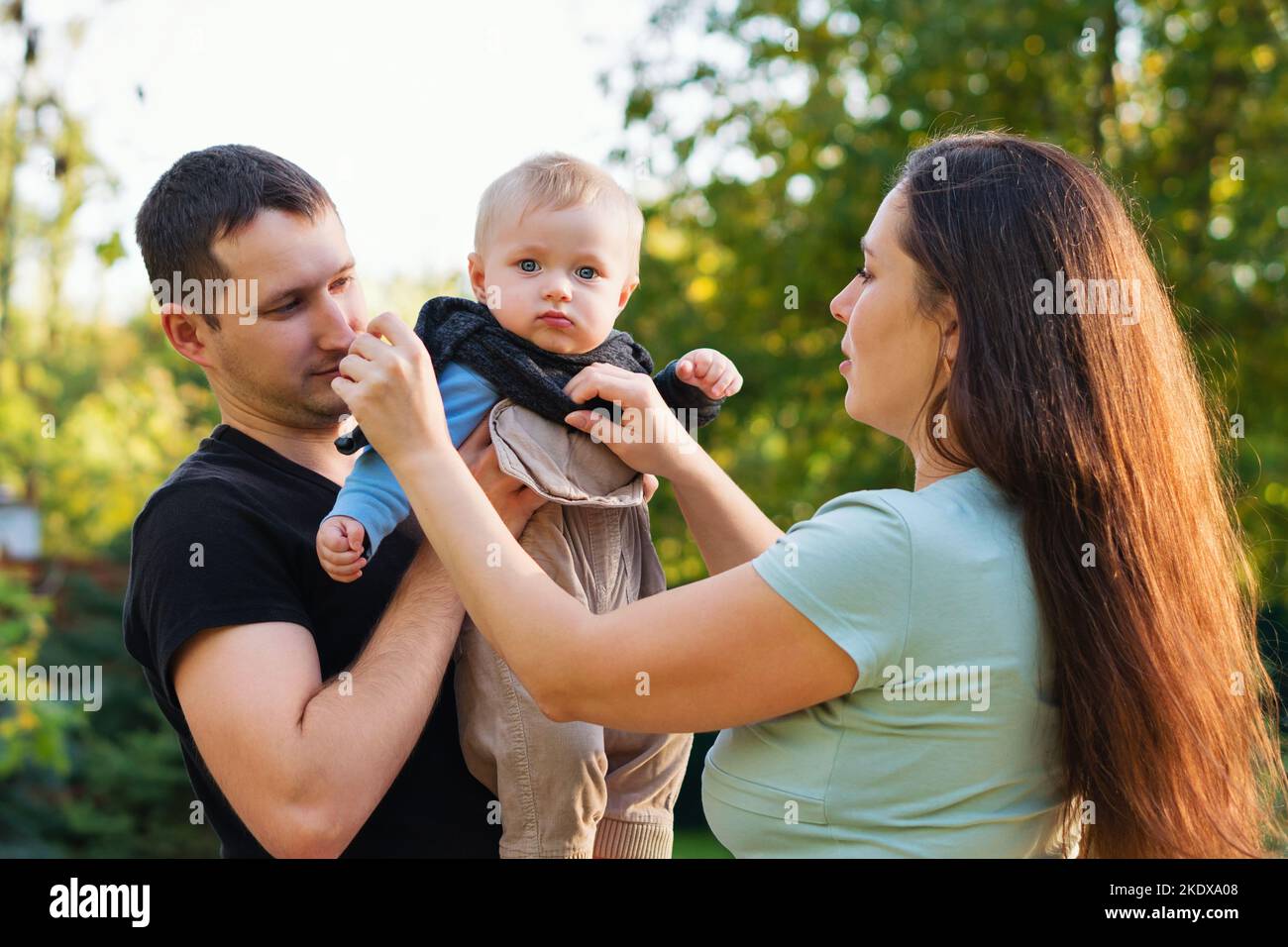 Mother, dad and kid baby son spending time together in summer park ...