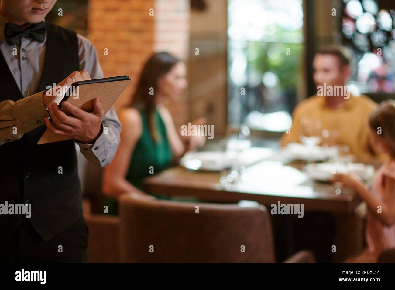 Restaurant waiter filling order details in application on table ...