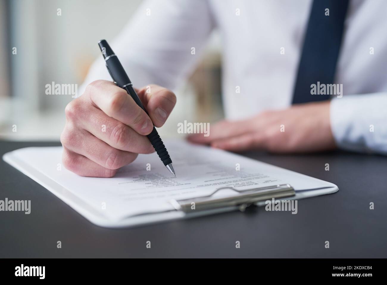 Putting pen to paper. a businessman filling out paperwork on a ...