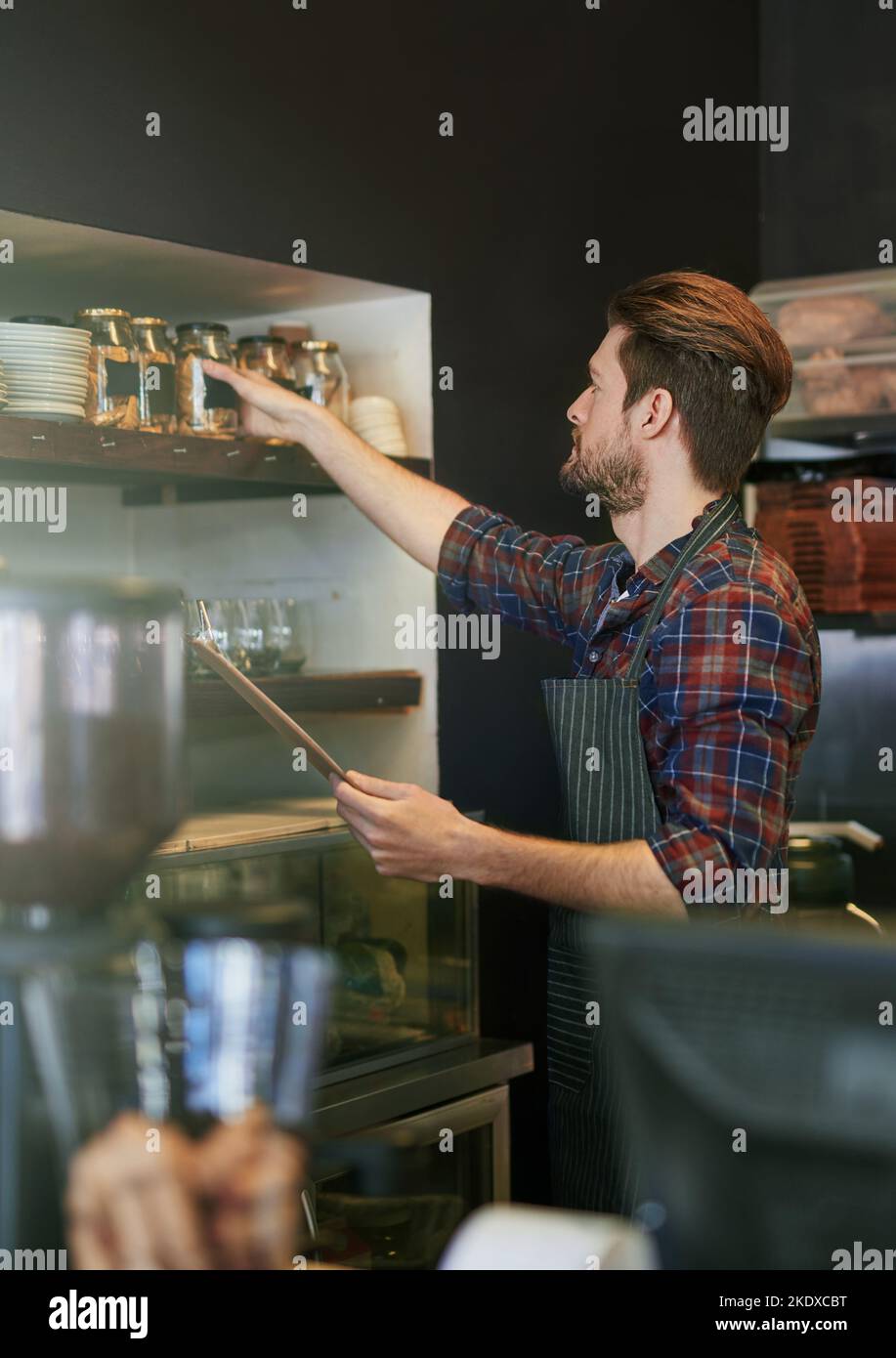 Making sure hes sufficiently stocked. a young cafe owner doing stock ...