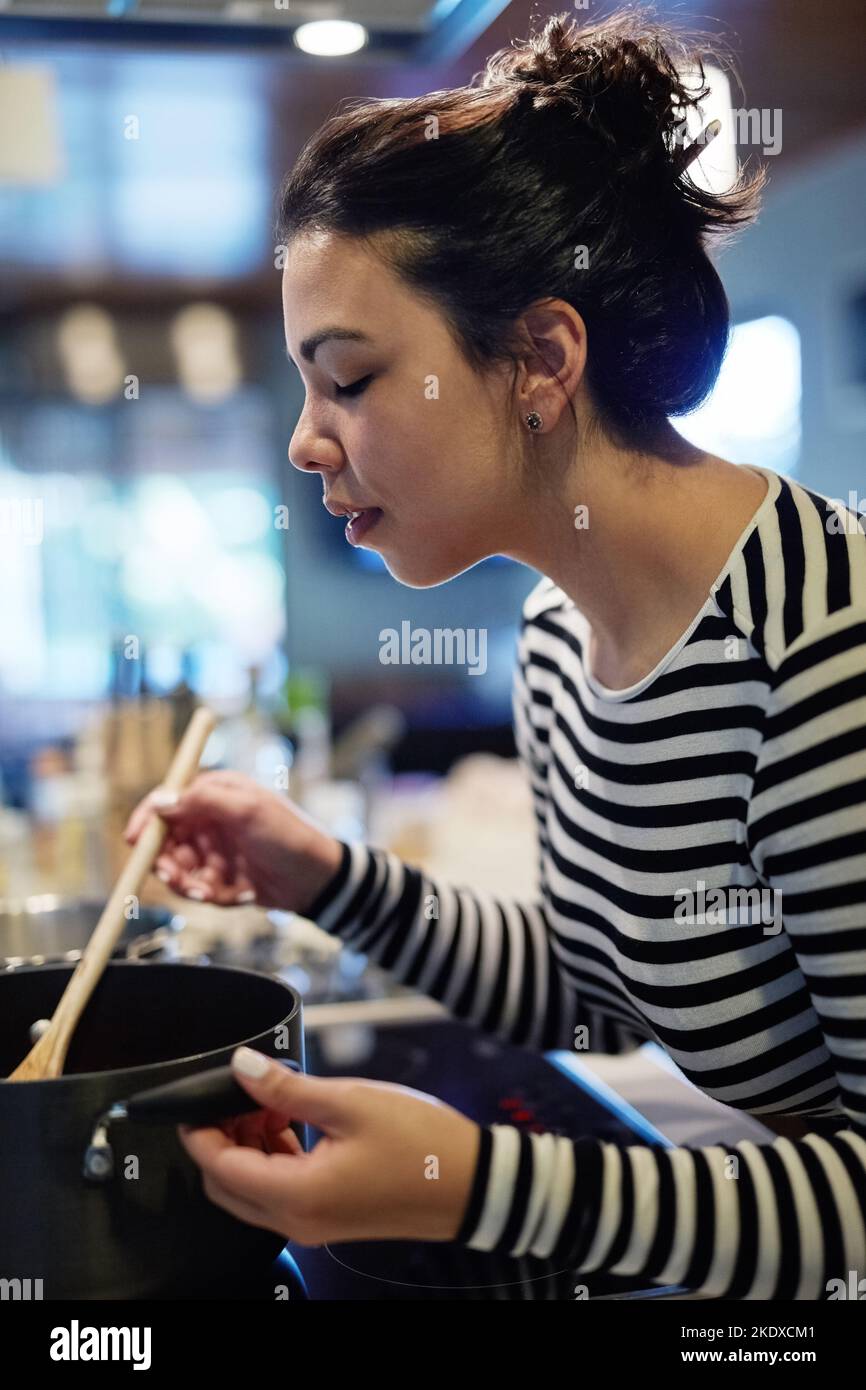 Cooking one of her classic dishes. an attractive young woman cooking in ...