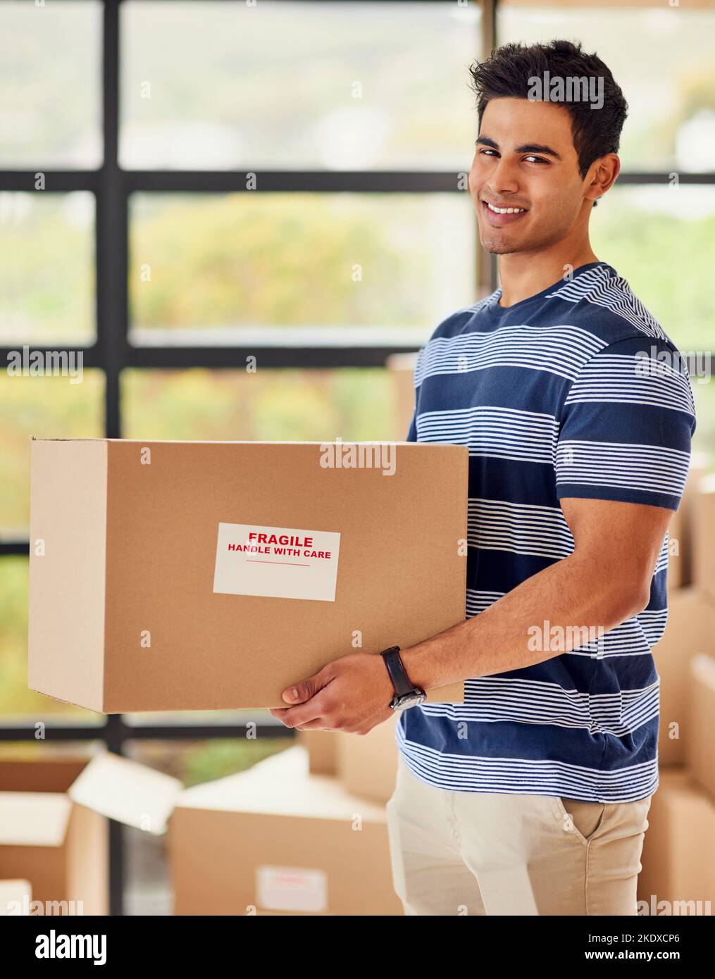 Packed and ready to move. Portrait of a smiling young man carrying a ...