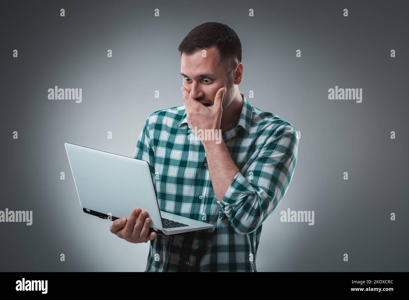 Frustrated businessman holding a laptop covers his face with his hand ...