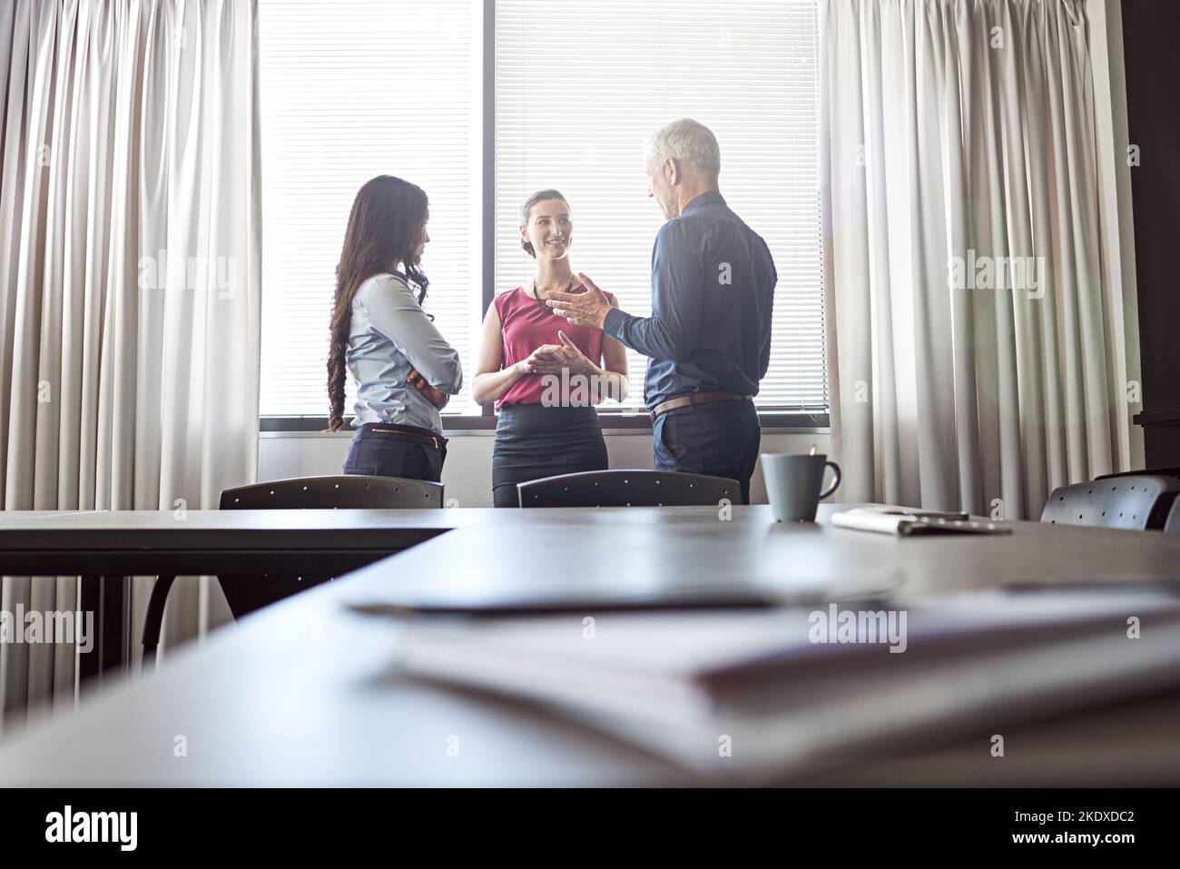 Talking it over. three businesspeople meeting in the office Stock Photo ...